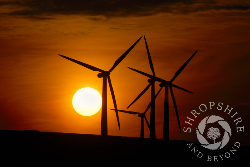 The sun goes down behind the turbines at Carno Wind Farm in Powys, Mid ...