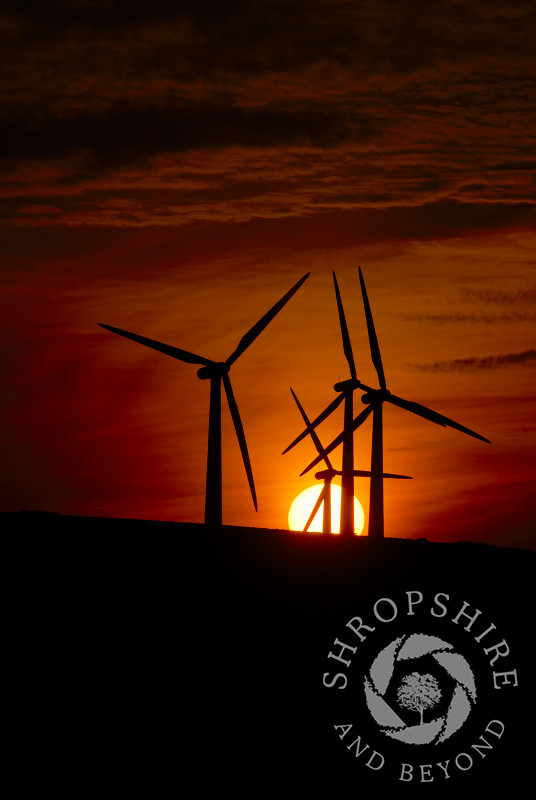 The sun goes down behind the turbines at at Carno Wind Farm in Powys ...
